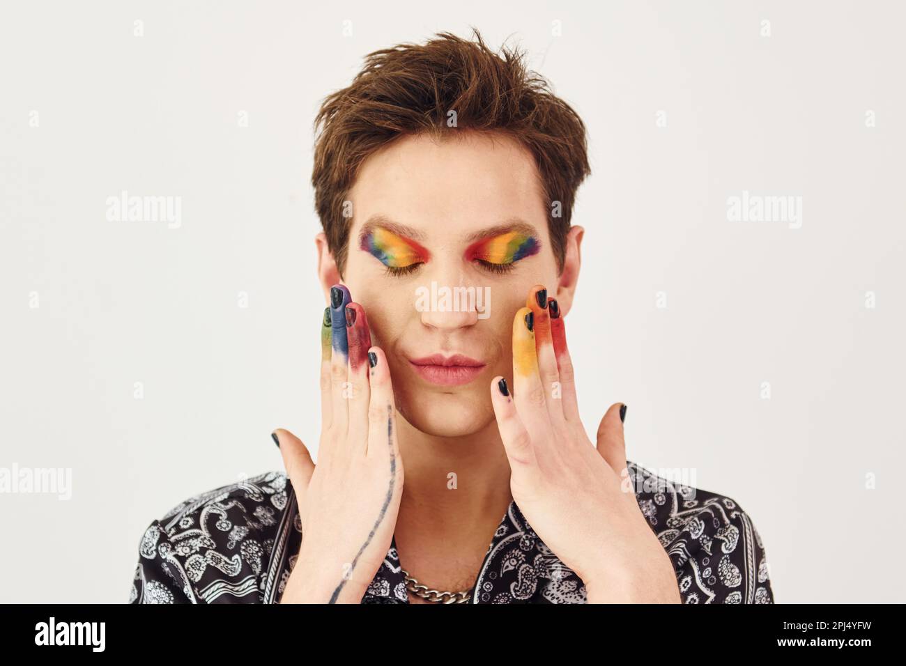 Young gay man is standing in the studio and posing for a camera ...