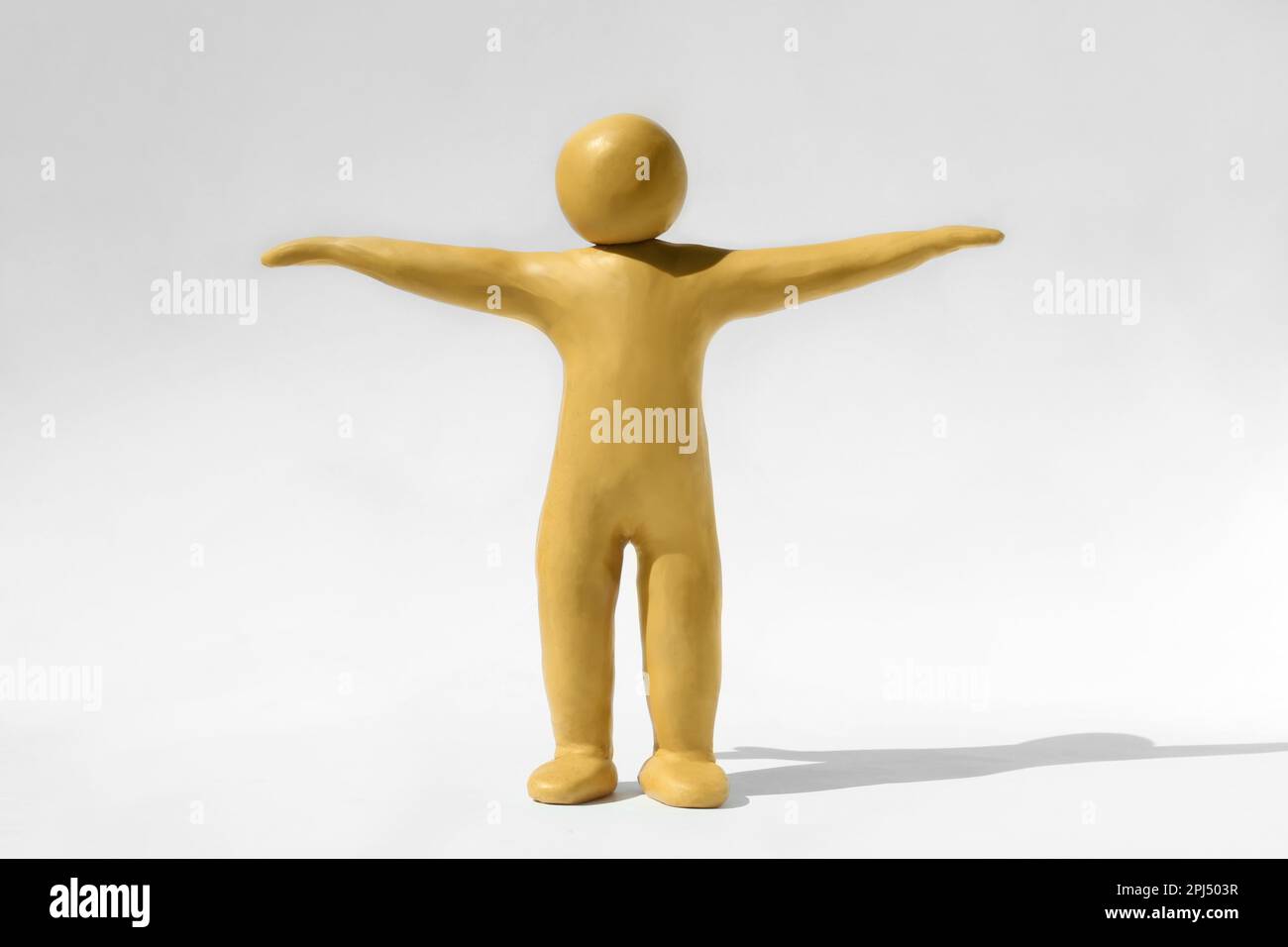 Human figure with arms wide open made of yellow plasticine on white ...