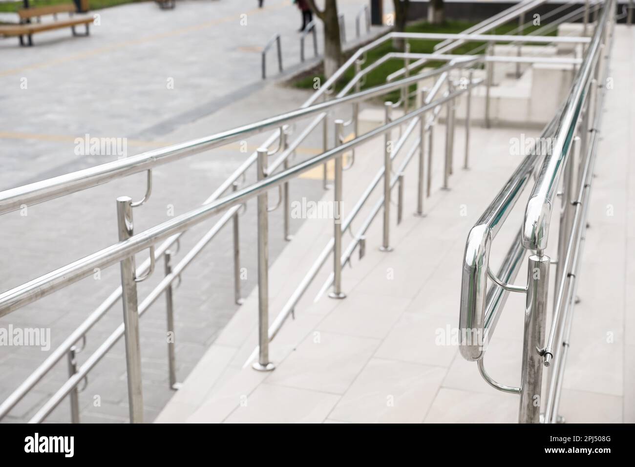 Tiled ramp with shiny metal railings outdoors Stock Photo - Alamy