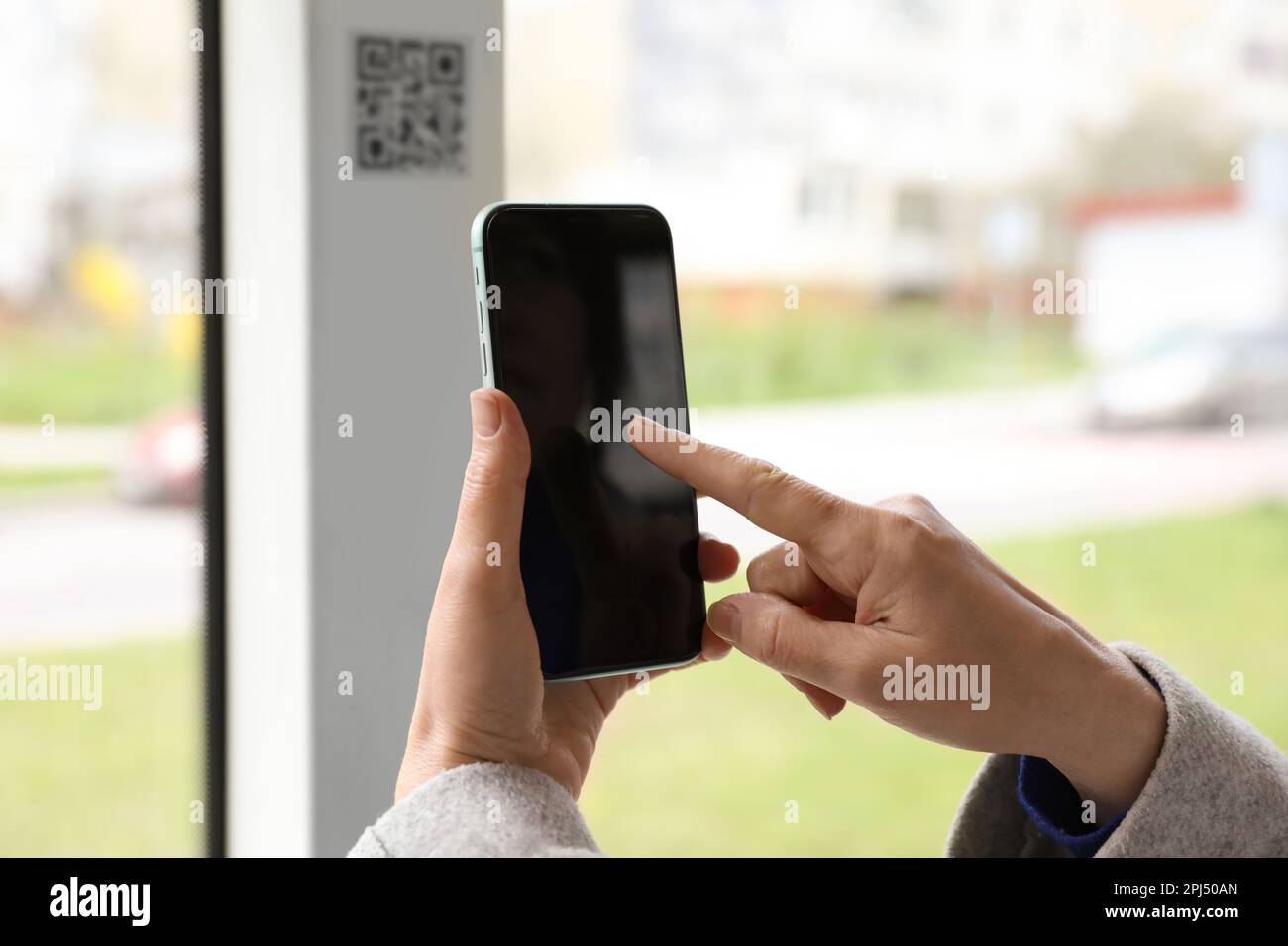 Woman scanning QR code with her smartphone in public transport, closeup ...