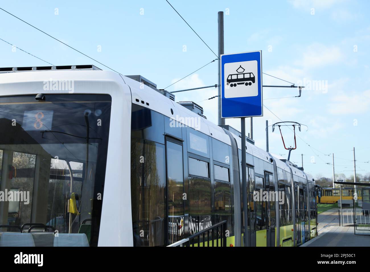 Modern streetcar near tram stop sign outdoors Stock Photo - Alamy
