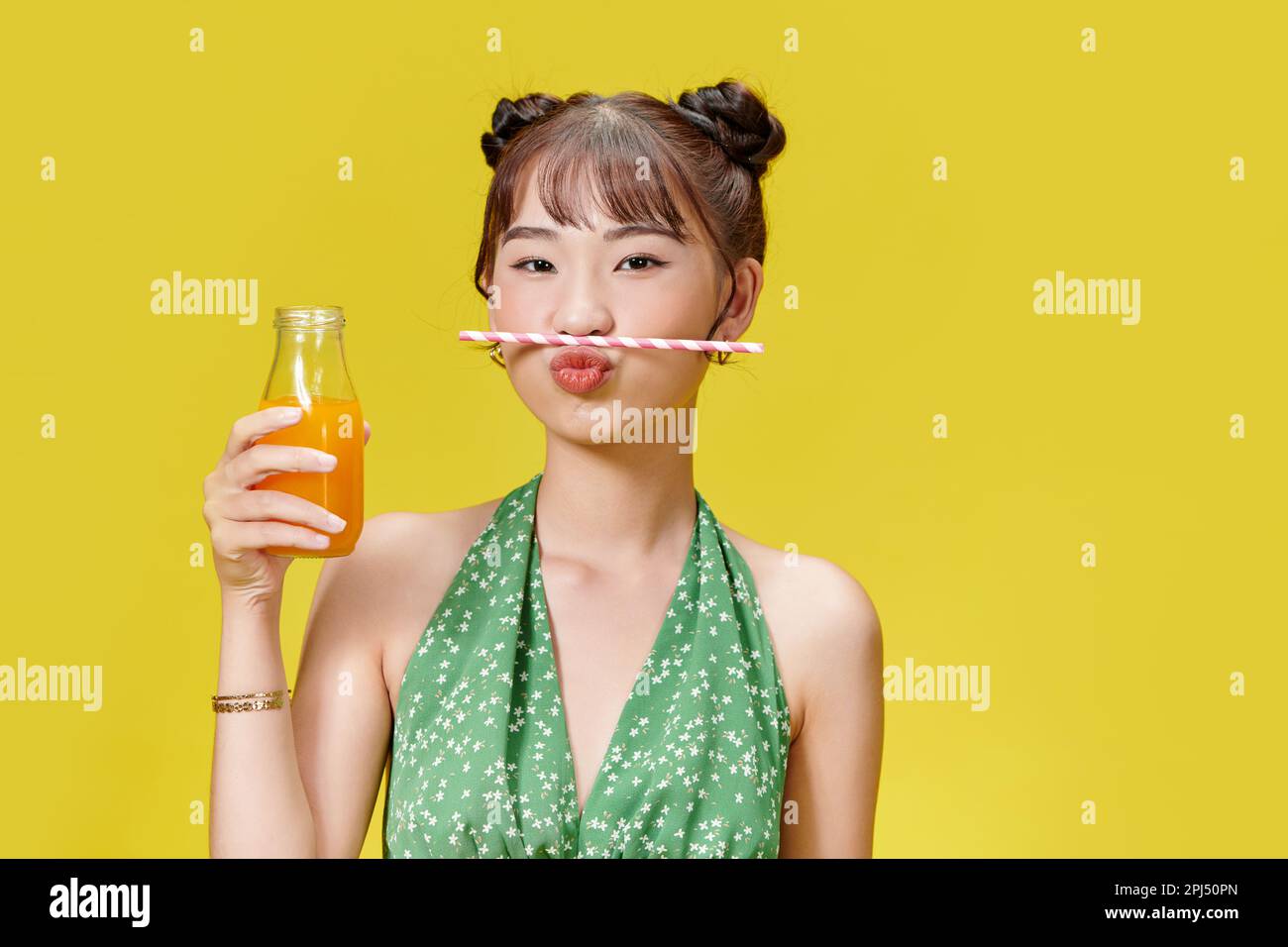 Young asian woman holding fresh orange juice from bottle, spending time ...