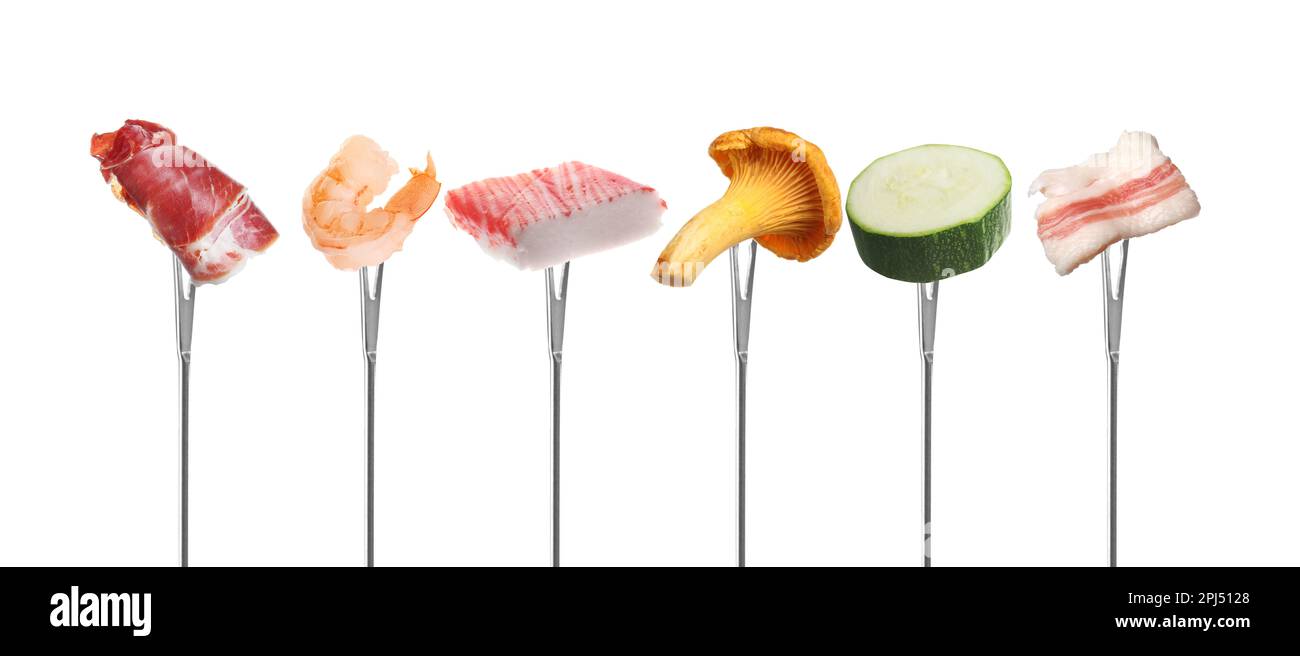 Forks with different tasty ingredients for fondue on white background ...