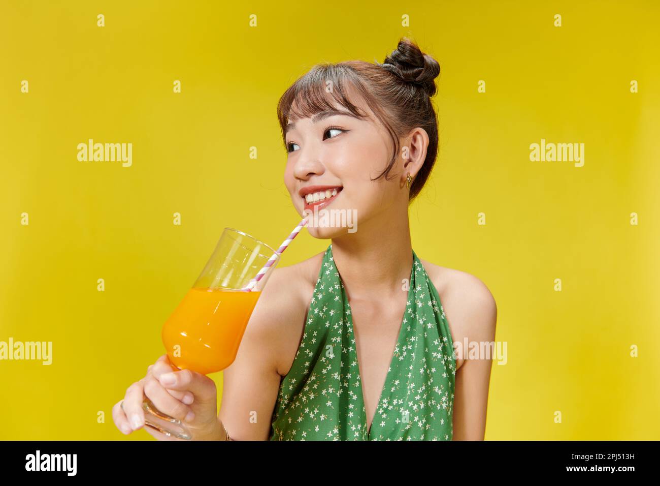 Beautiful woman drinks cocktail on yellow background Stock Photo - Alamy