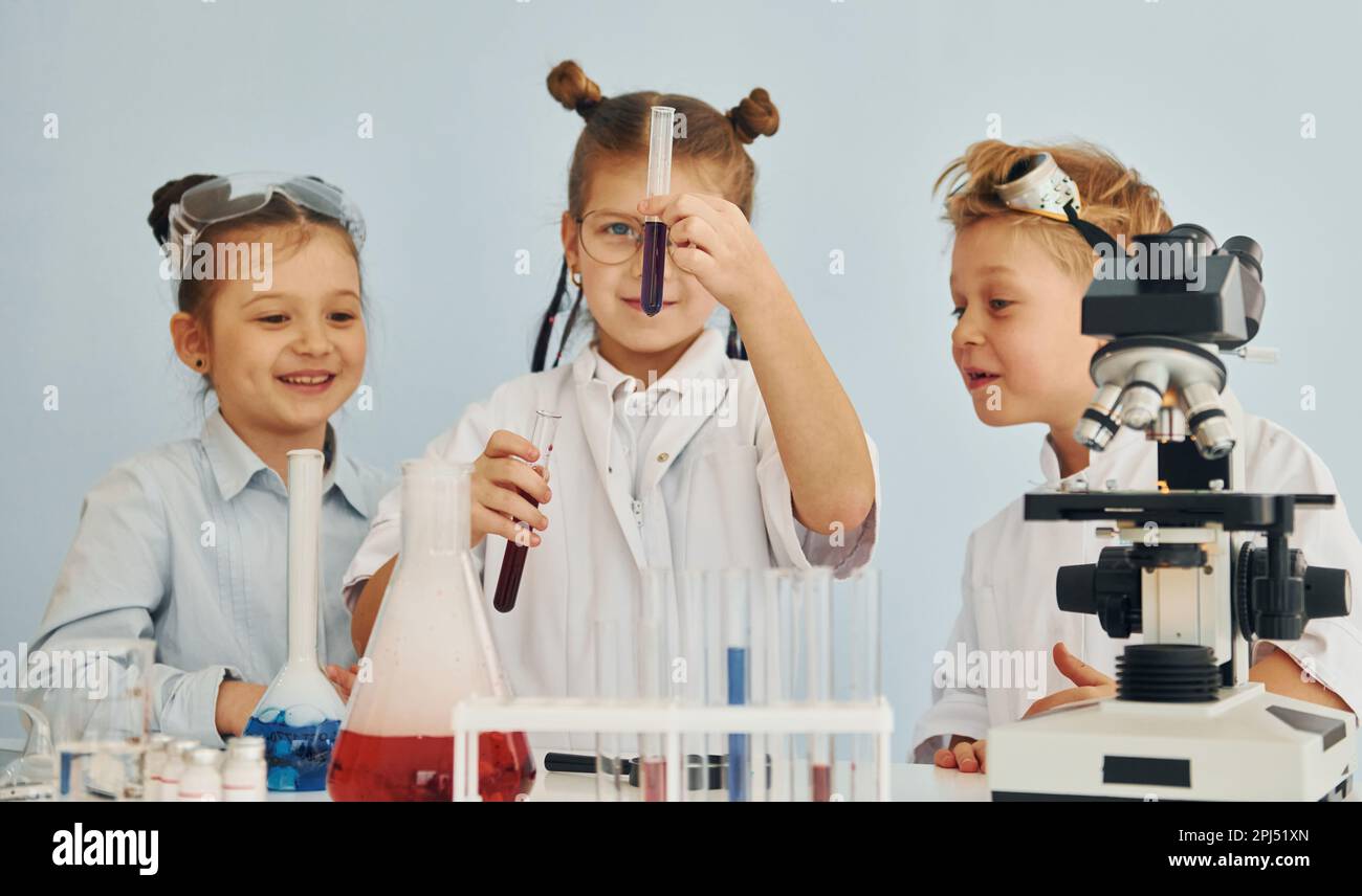 Test tubes with colorful liquid. Children in white coats plays a ...