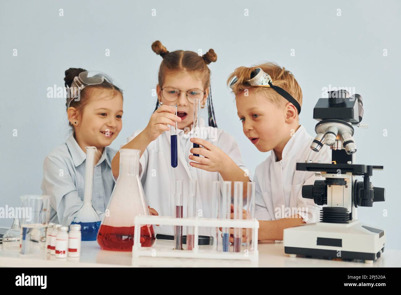Test tubes with colorful liquid. Children in white coats plays a ...