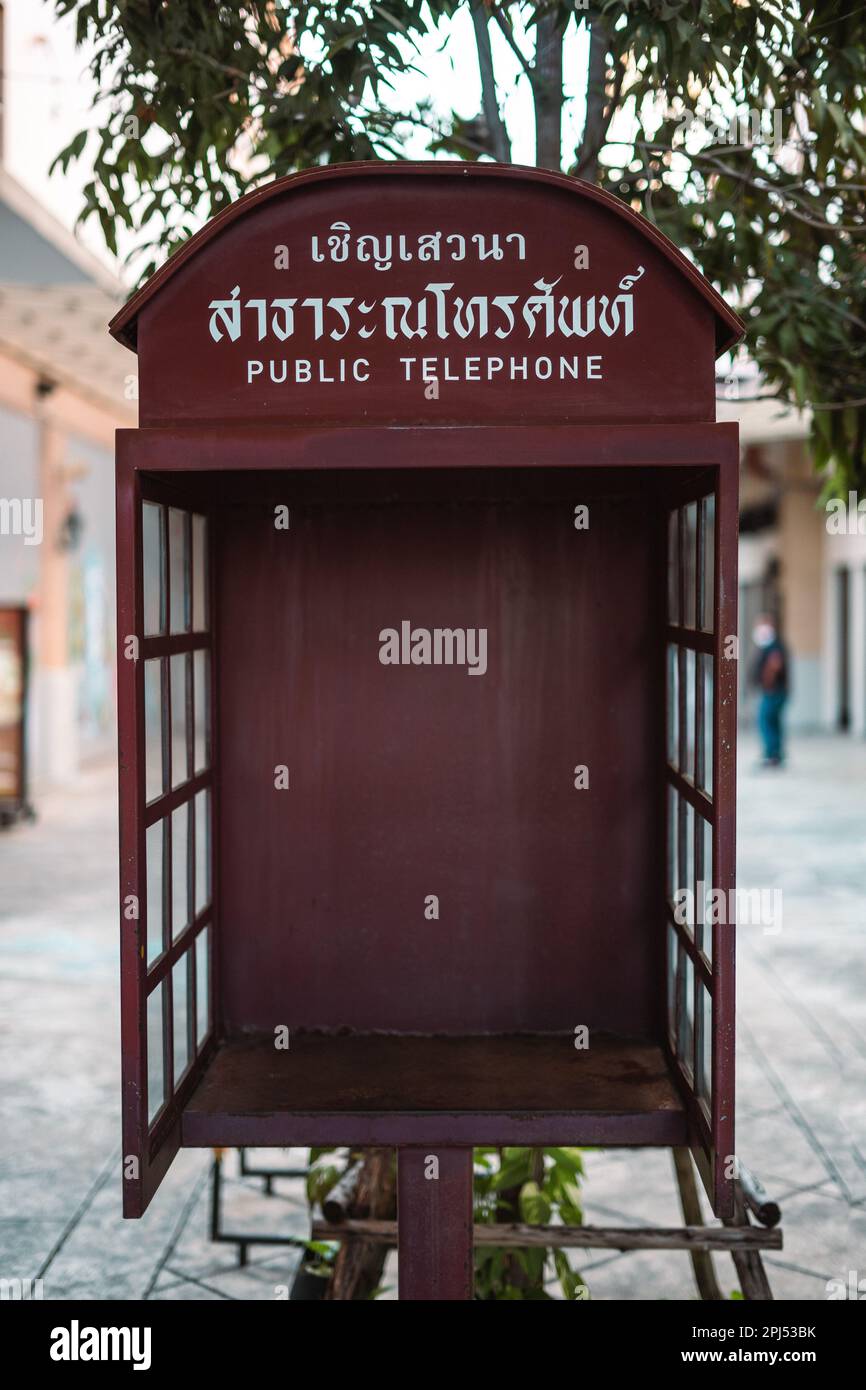 A red classic public telephone box stands isolated in an urban ...