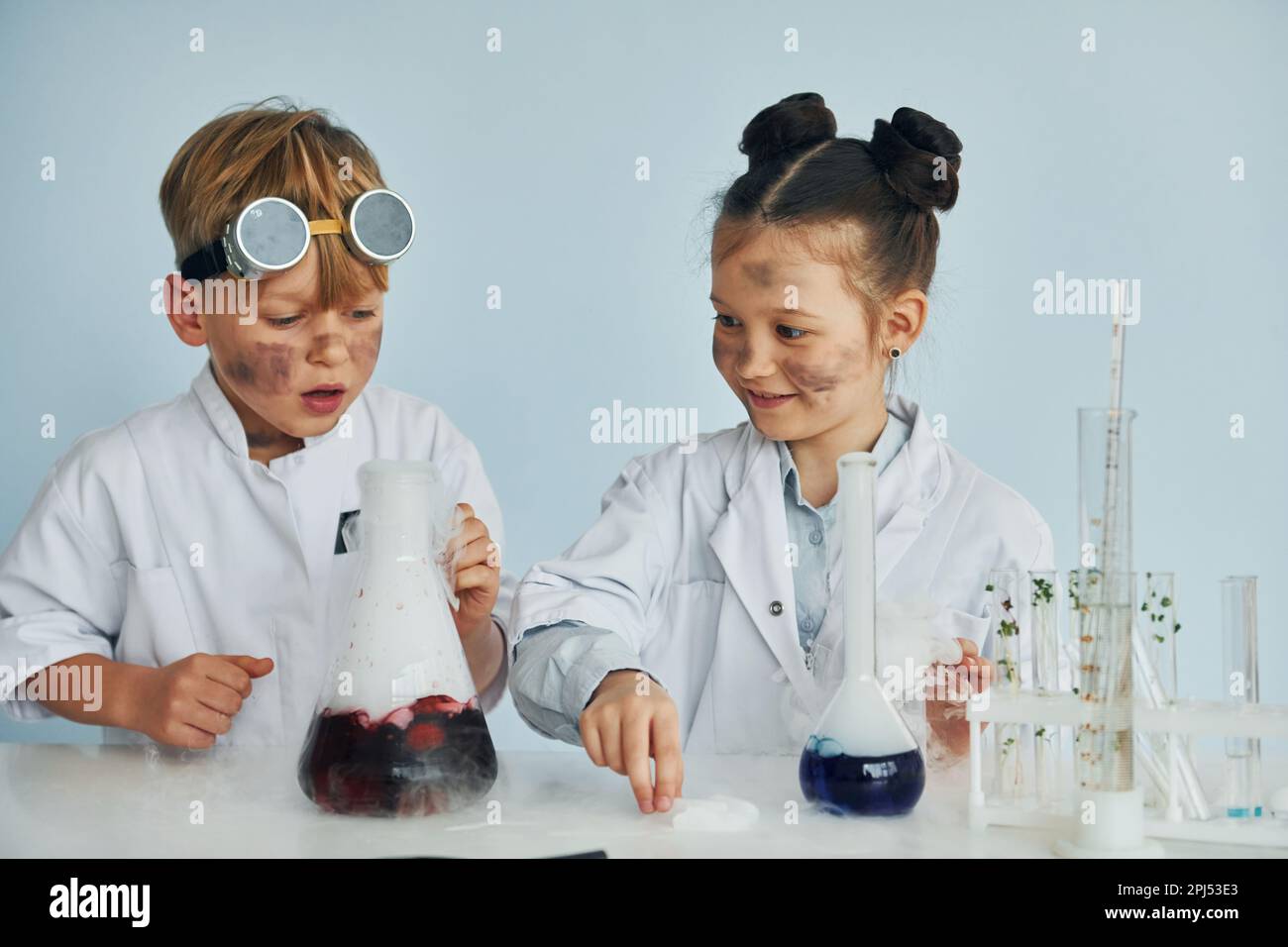 Boy works with liquid in test tubes. Children in white coats plays a ...