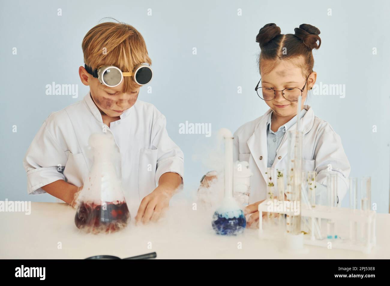 Girl with boy working together. Children in white coats plays a ...