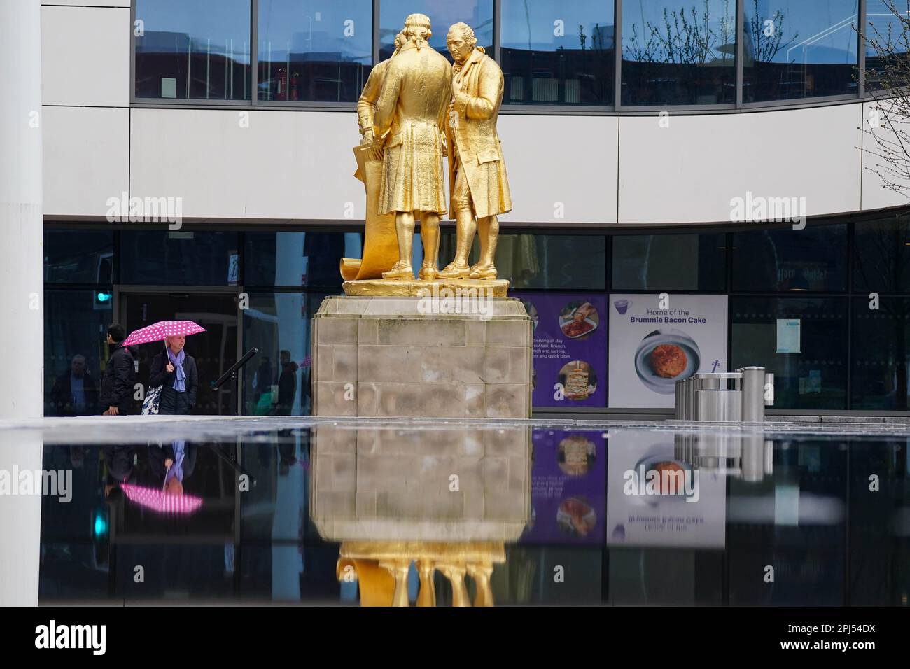 A woman walks by the 'golden boys' statue, featuring Matthew Boulton ...