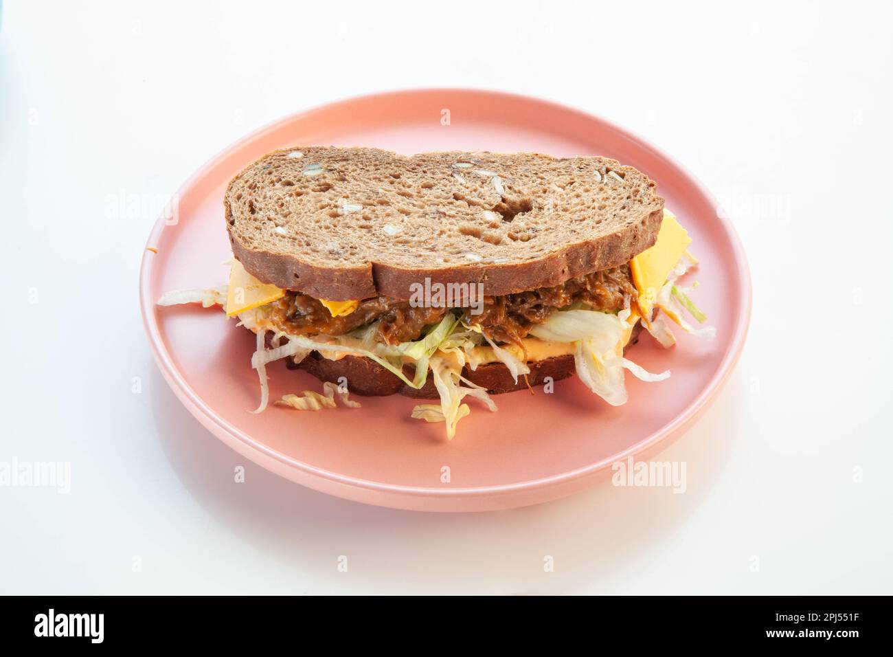 Rye bread pulled beef sandwich on a pink plate white background Stock ...