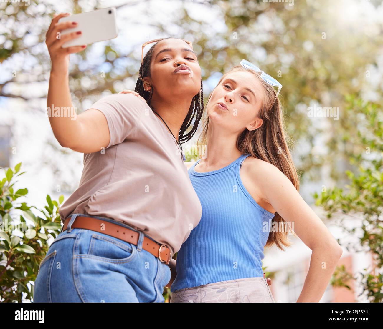 Selfie, kiss and women friends bonding, chilling or hanging out outdoor ...