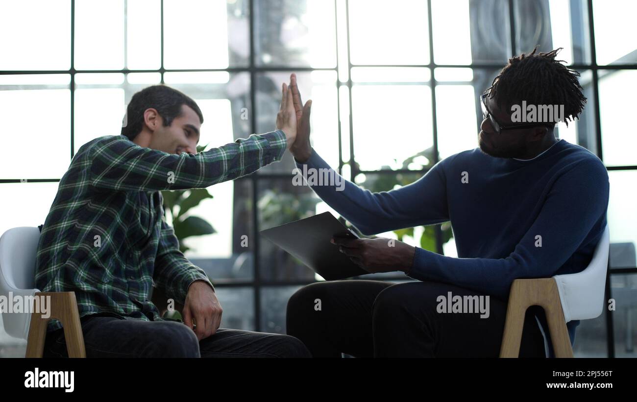 Business partners shaking hands sit on chairs in office lobby start or ...