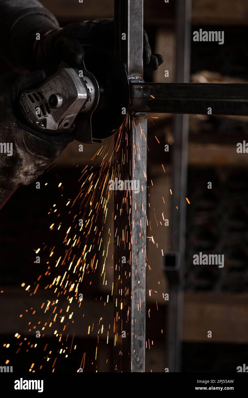 Closeup photo of metalworking in dark workshop. Welding and grinding ...