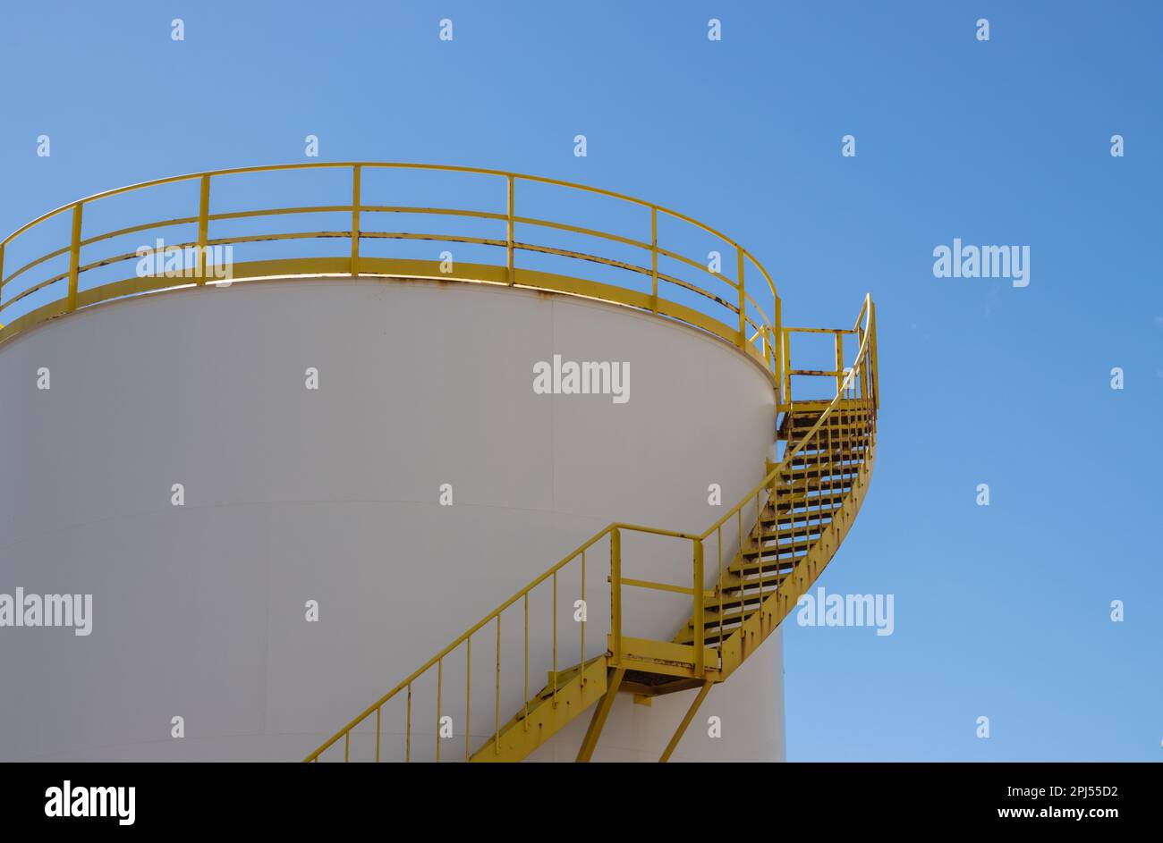 White tank with yellow staris and railing on the top. Bright blue sky ...