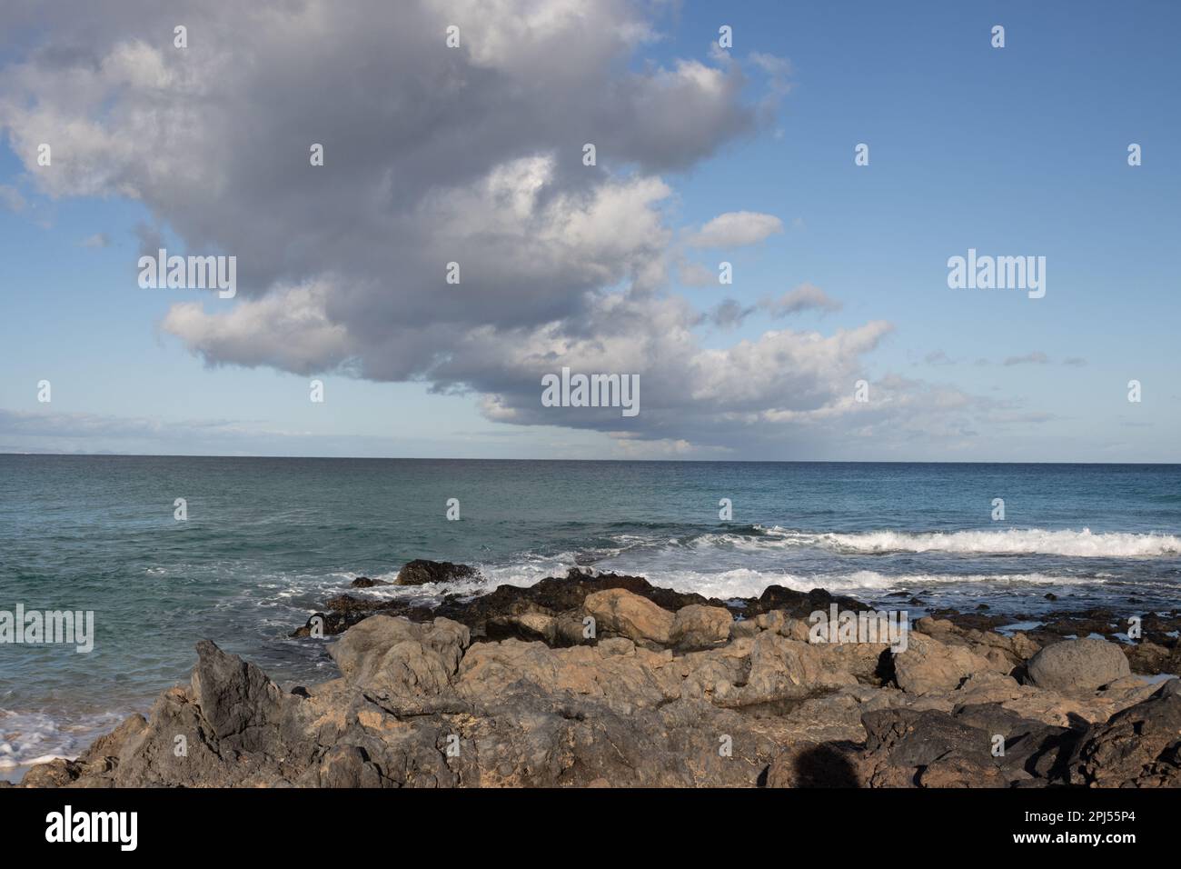 Rocky coast at the beach of Atlantic ocean. Blue sky with white clouds ...