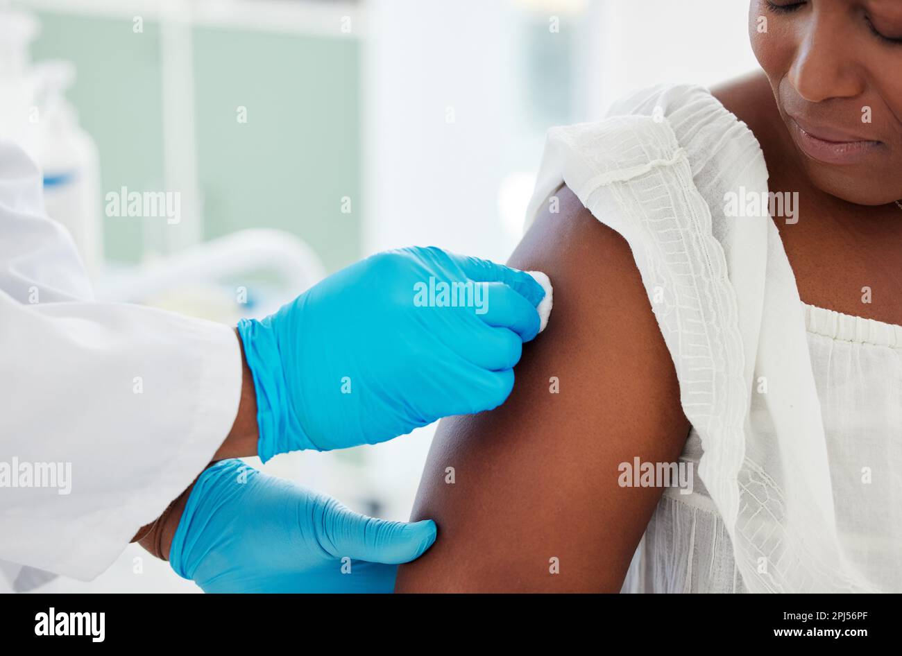 Medical doctor cleaning an arm before an injection in a consultation ...