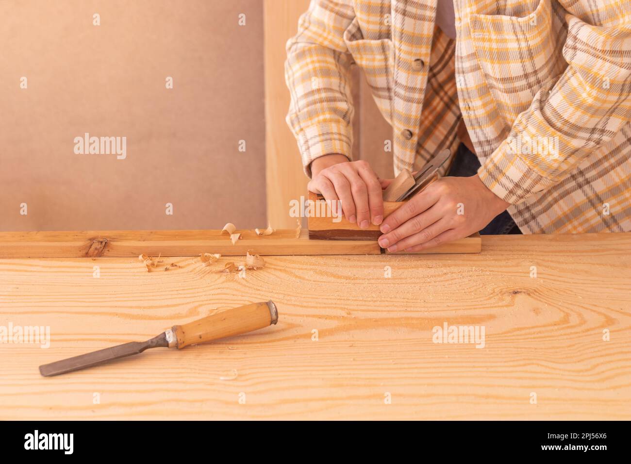 Unrecognizable male woodworker smoothing wooden detail with jack plane ...