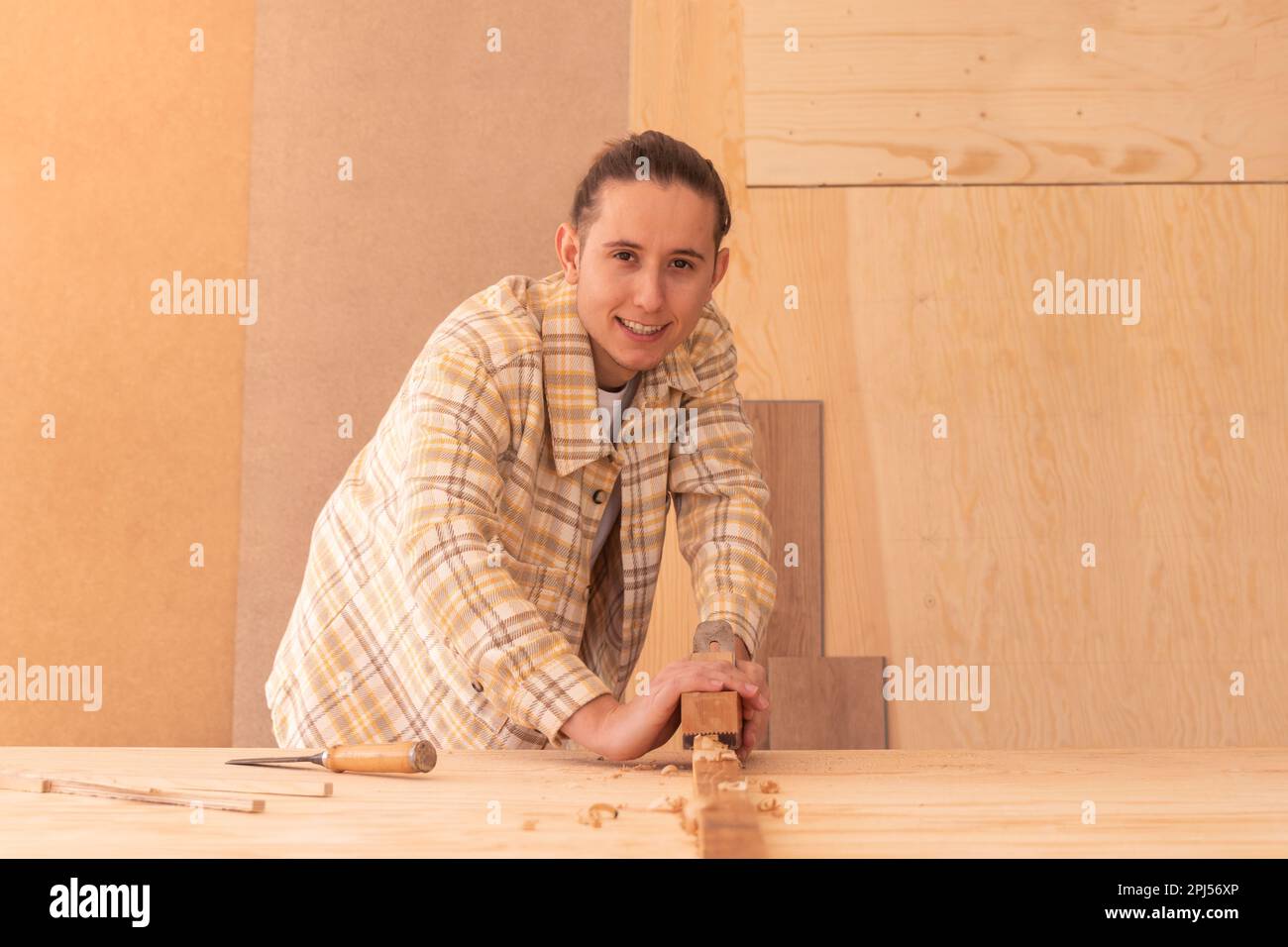 Happy male woodworker looking at camera and smiling while smoothing ...