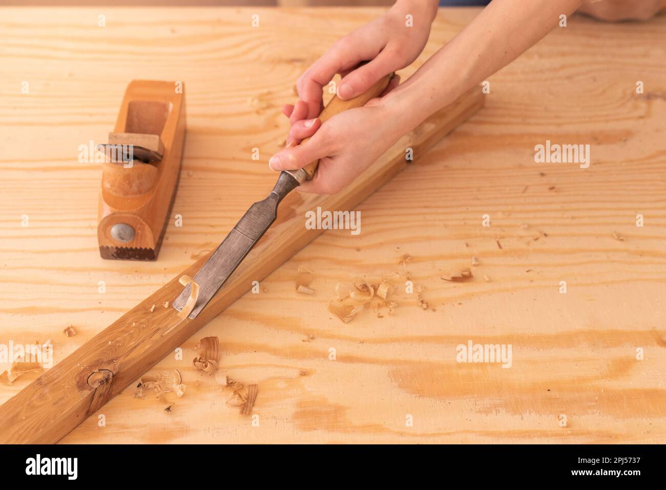 Top view of body part of anonymous carpenter carving wood on plank with ...