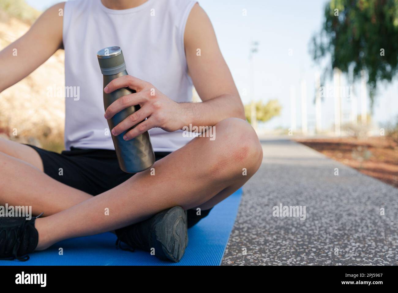 An athlete holding a bottle of water during a workout, hydration in ...
