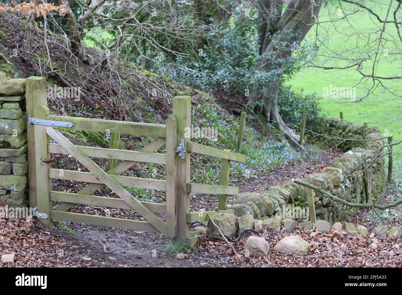 Wooden gateway onto a footpath leading down a countryside lane Stock ...
