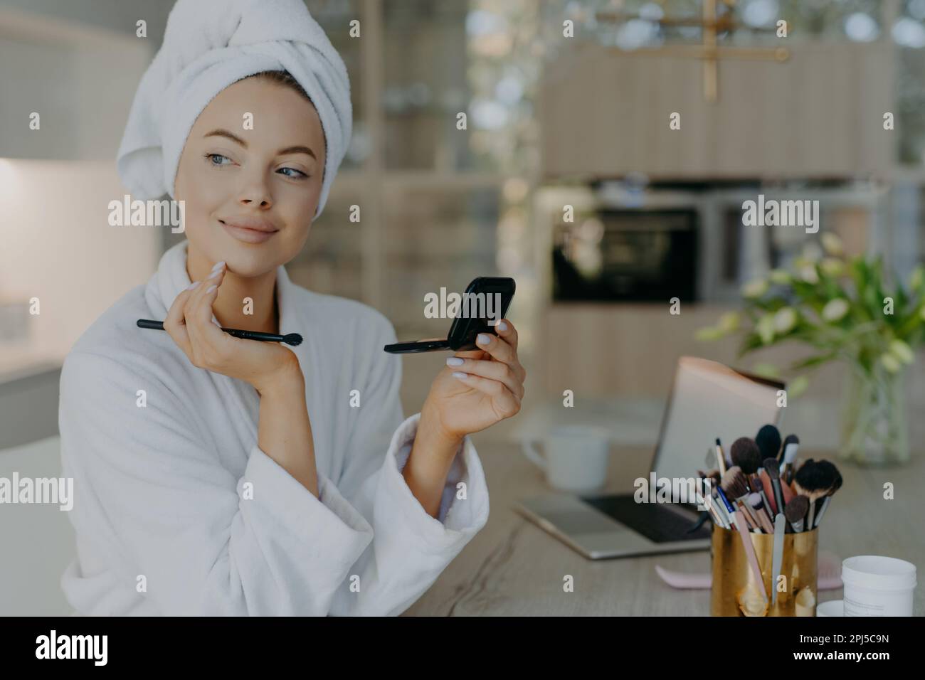 Tender young woman has morning routine applies daily makeup holds ...