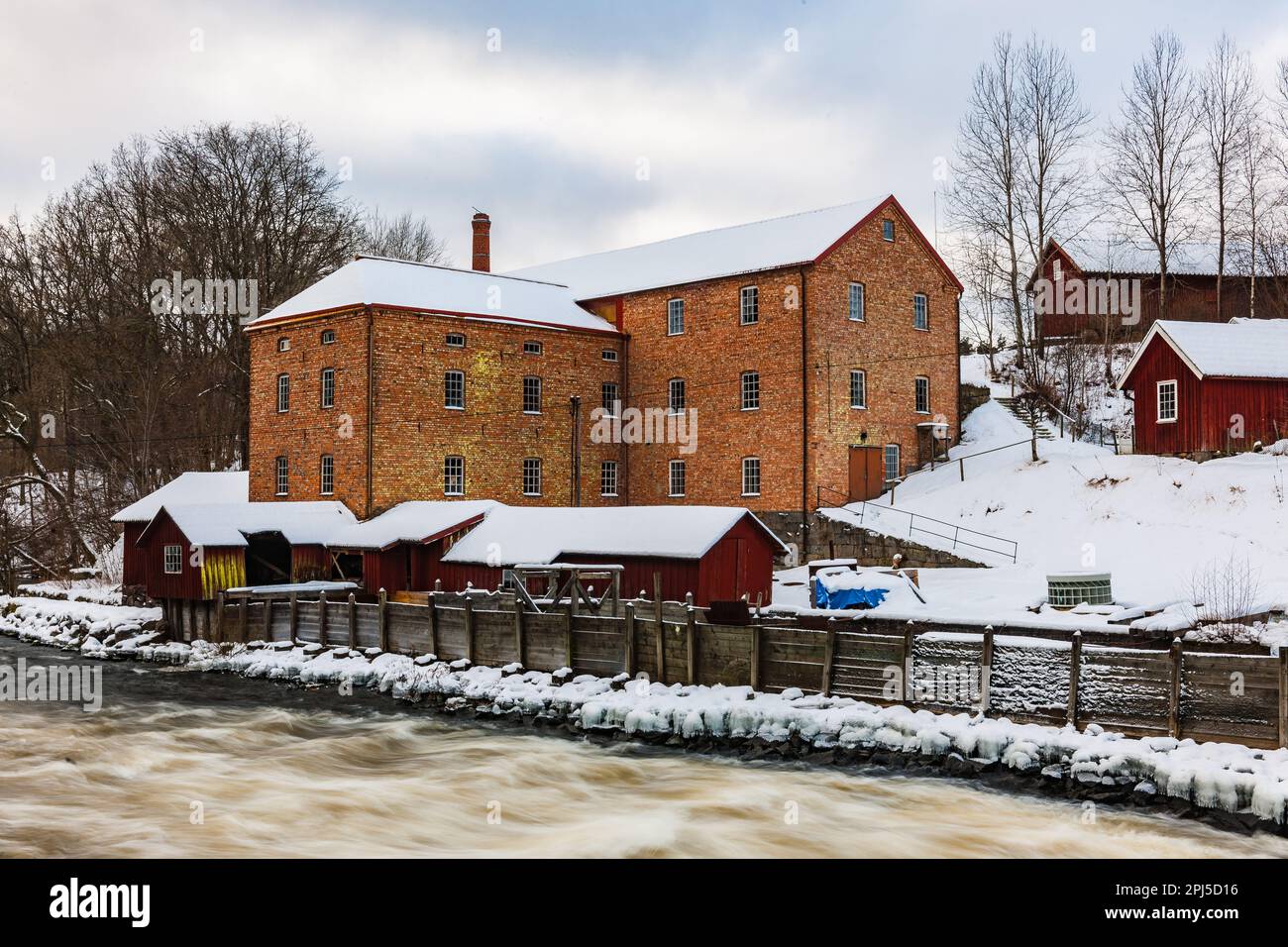 An old, brick factory building sits alone in the cold Swedish winter. A ...