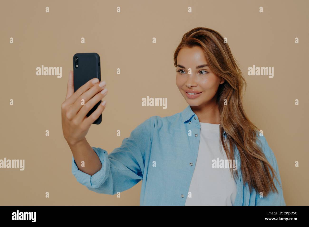 Adorable female model poses for making selfie, uses modern cell phone ...