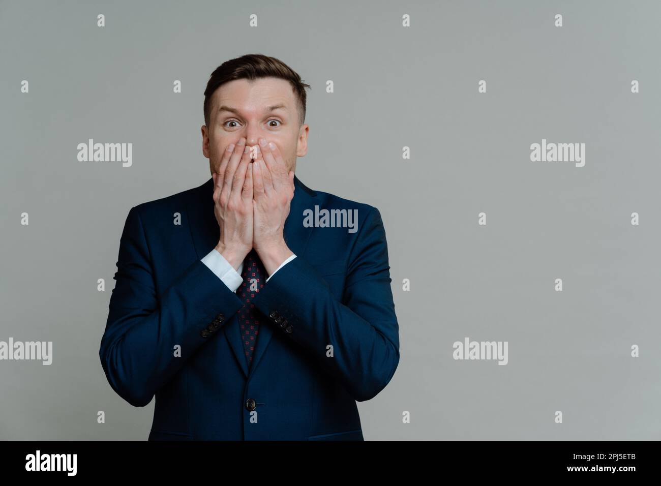 Shocked businessman in suit feeling stressed worried and covering mouth ...