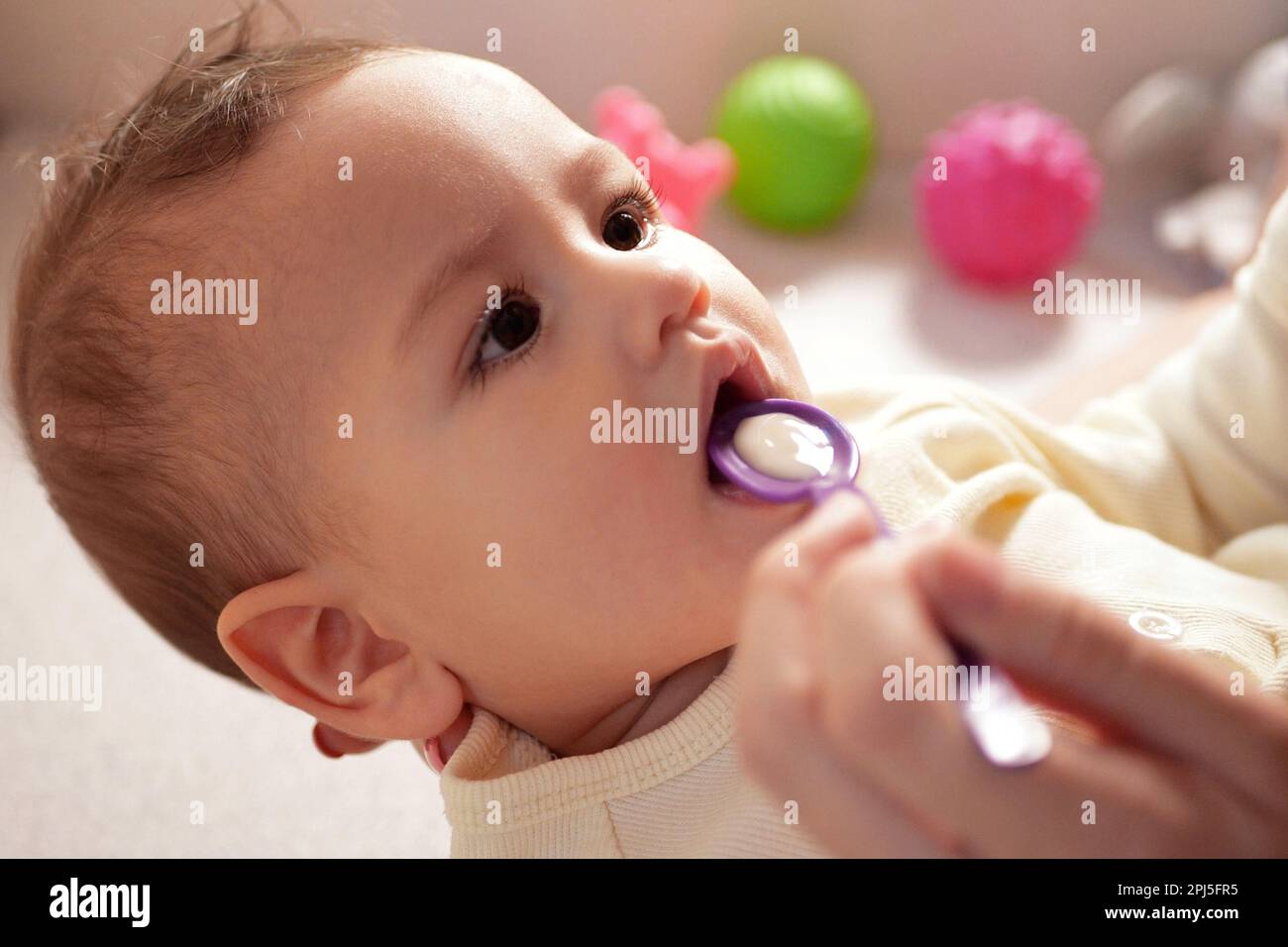 Newborn child drinking water or medicine cough syrup with spoon, close ...