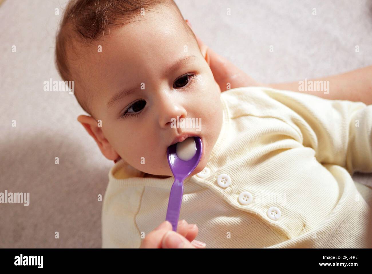 Newborn child drinking water or medicine cough syrup with spoon, close ...