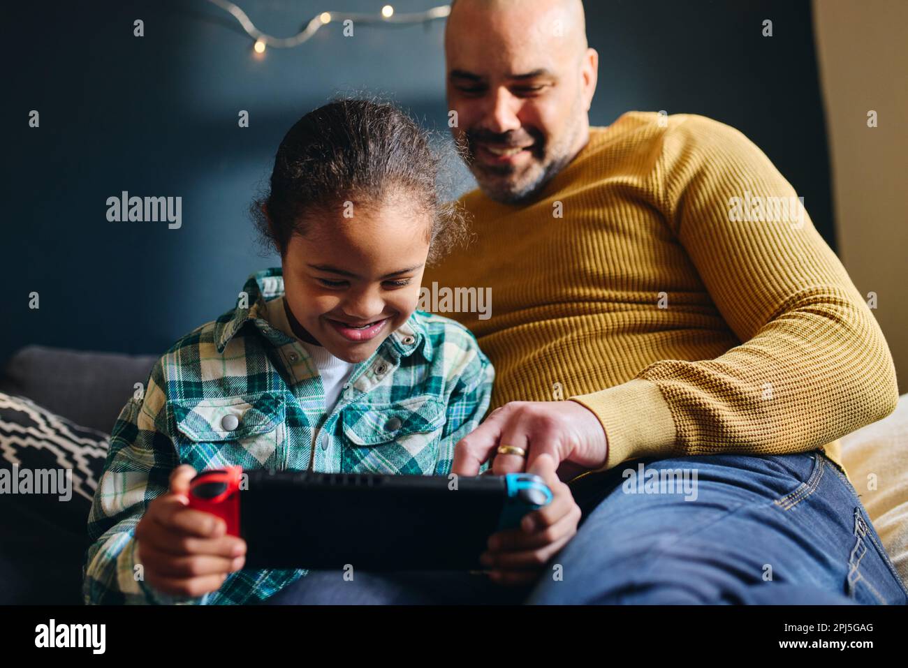 Boy with Down syndrome smiling and playing computer game with father ...