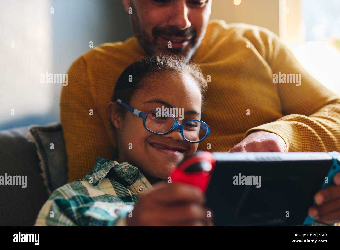 Boy with Down syndrome smiling and playing computer game with father ...