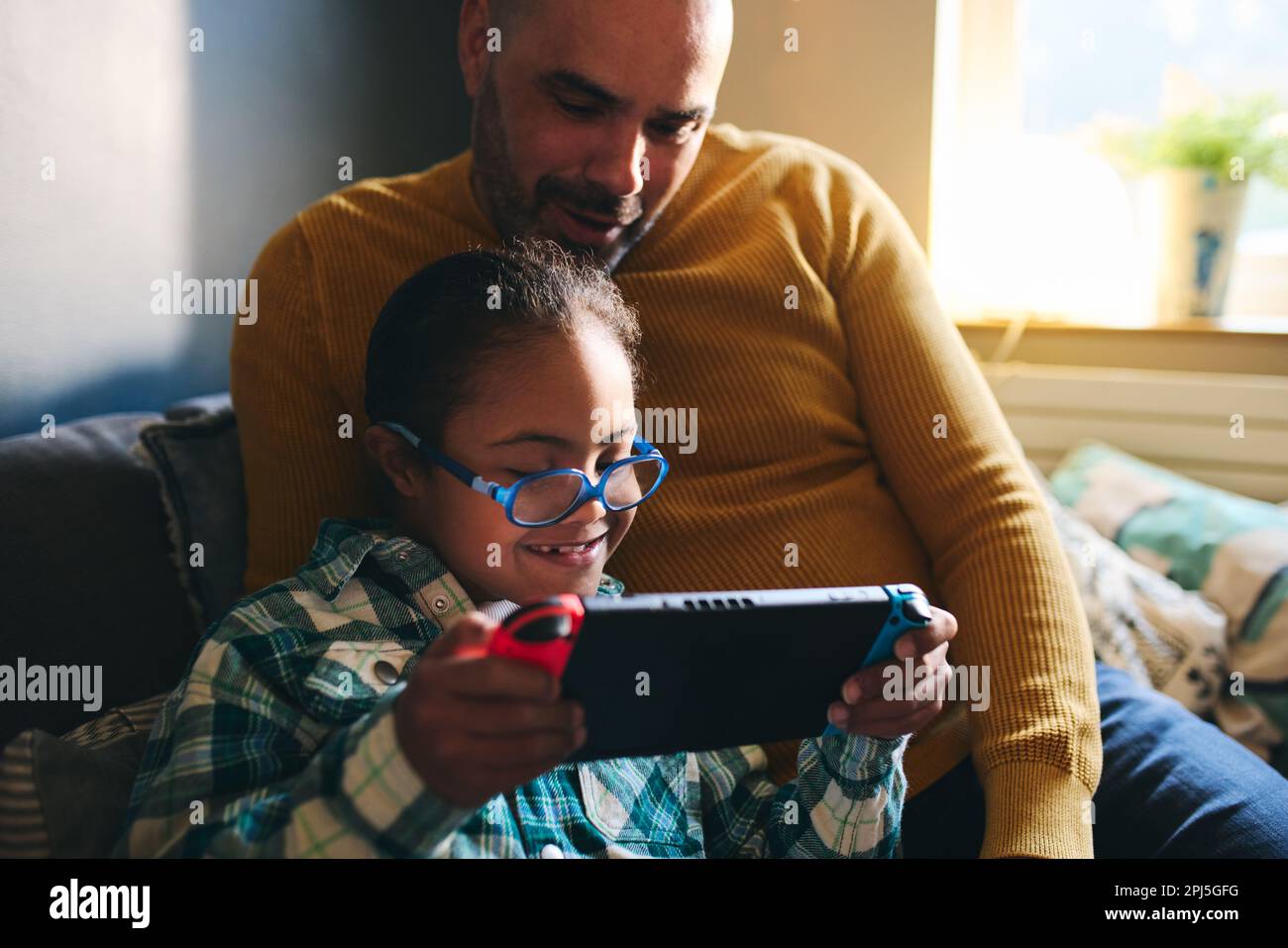 Cheerful boy with Down syndrome playing computer game with his father ...
