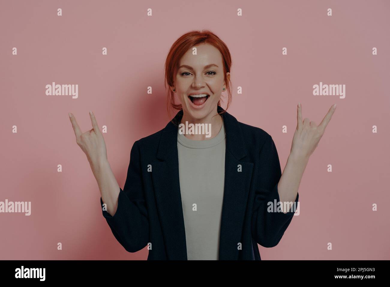 Heavy metal. Crazy red haired european woman showing sign of horns ...