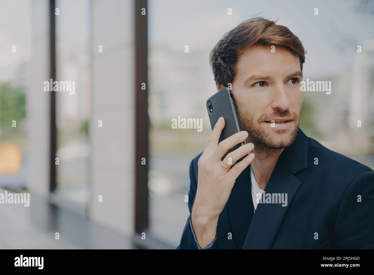 Pensive male entrepreneur focused into distance makes answering call ...