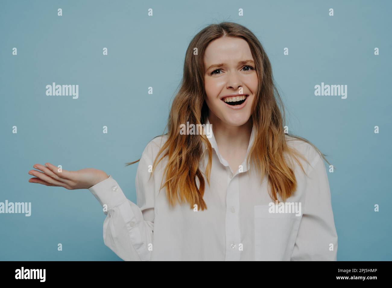 Positive happy female teenager in white shirt presenting something on ...