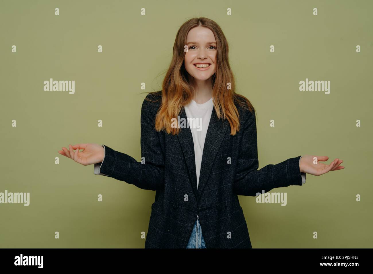 Smiling positive female shrugging shoulders with spreaded hands and ...