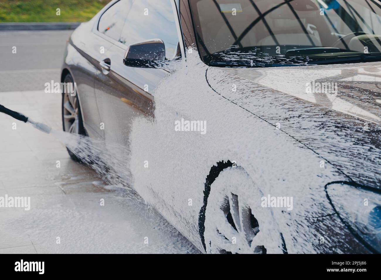 Black dirty car in white soap foam at car wash service station, vehicle ... Black dirty car in white soap foam at car wash service station, vehicle ...