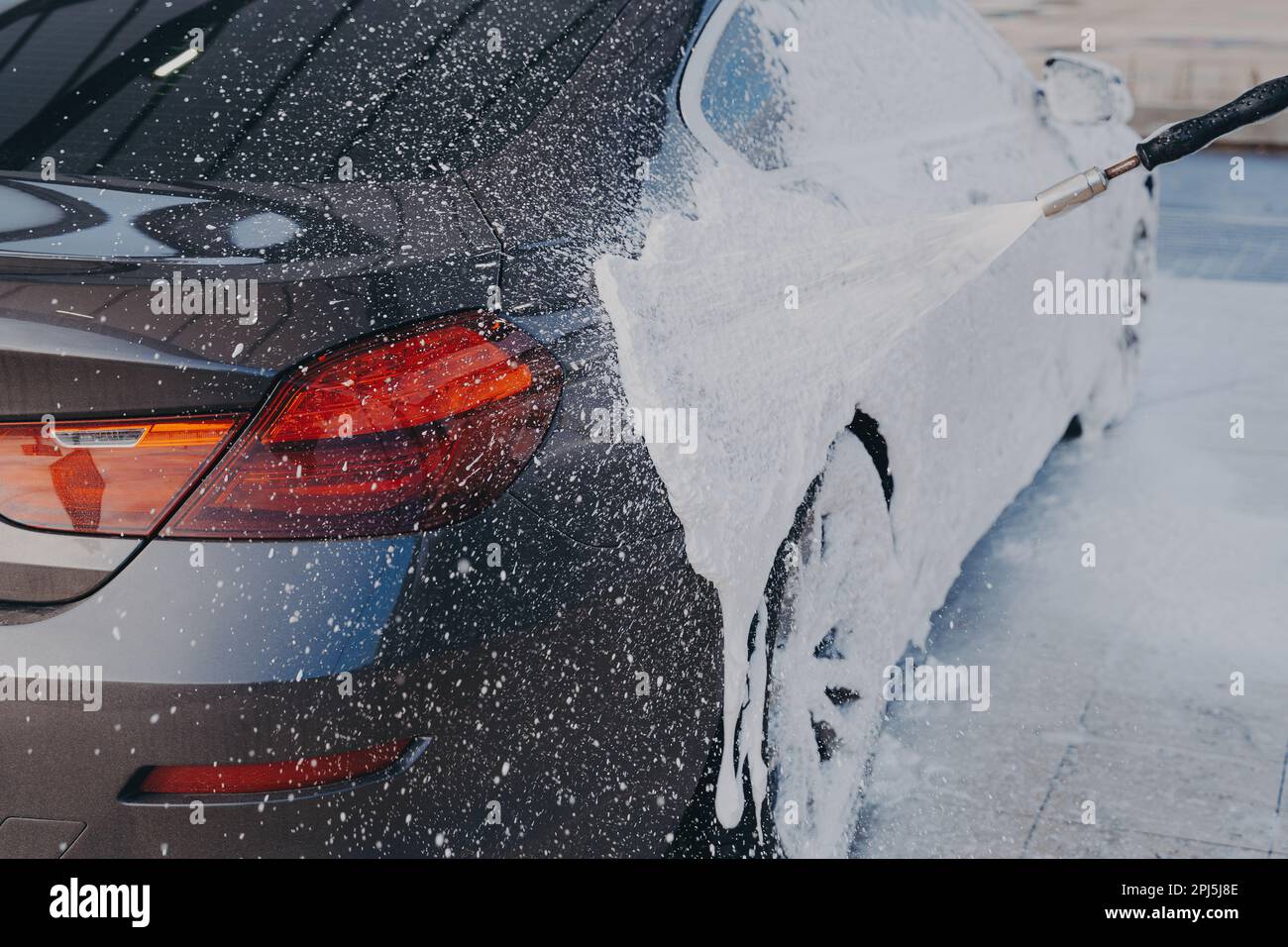Car exterior cleaning. Applying snow foam on dirty auto surface from ...