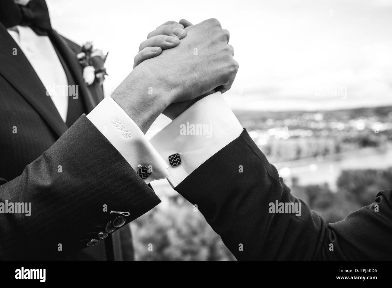 A greyscale shot of the groom giving a handshake to one of the guests ...