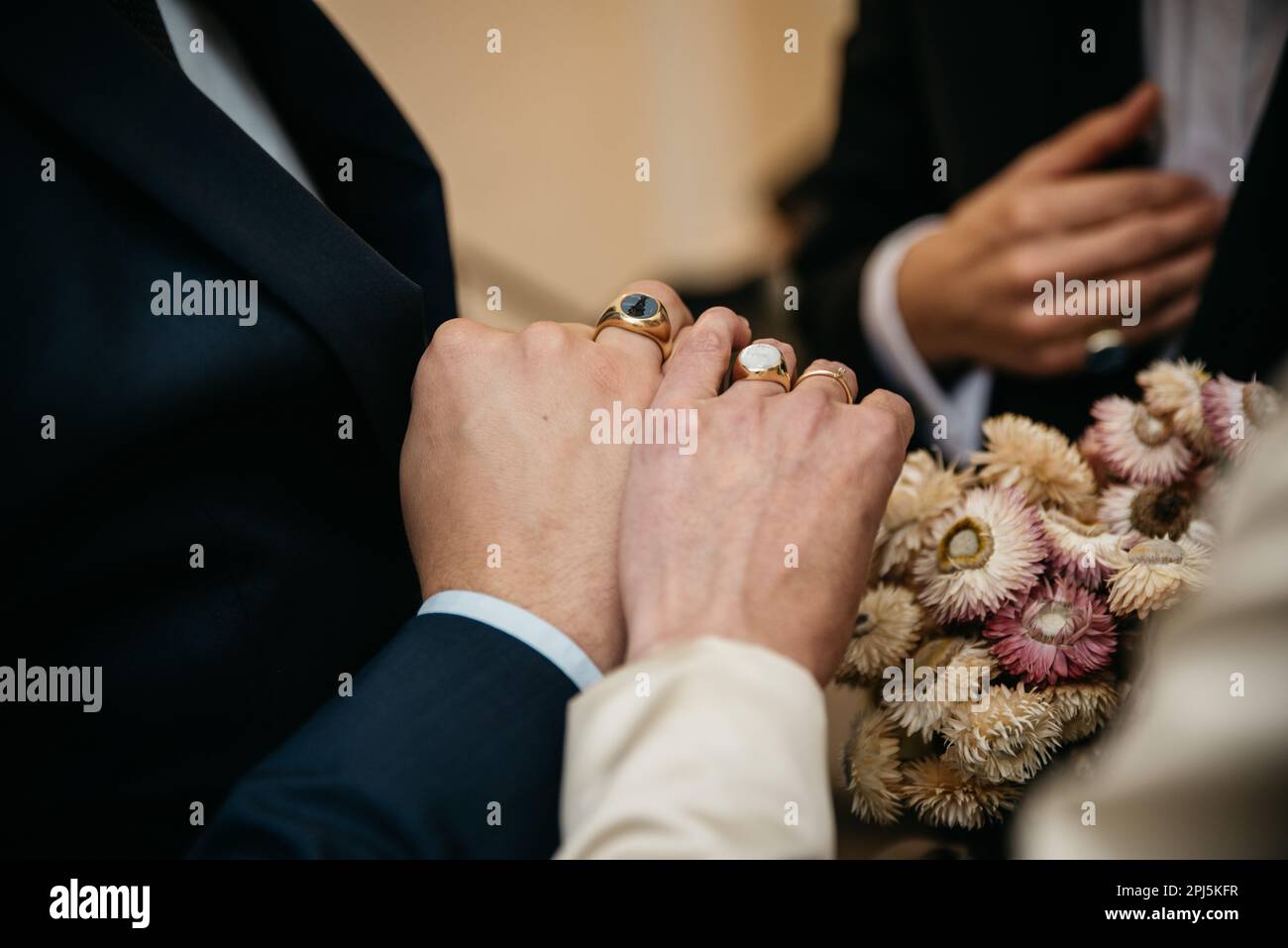 A close-up of a couple's hands featuring their wedding rings ...