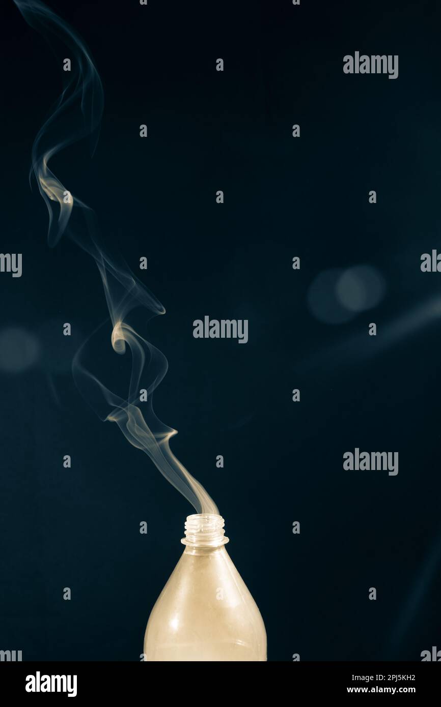 Smoke coming out of a plastic bottle against a black background with ...