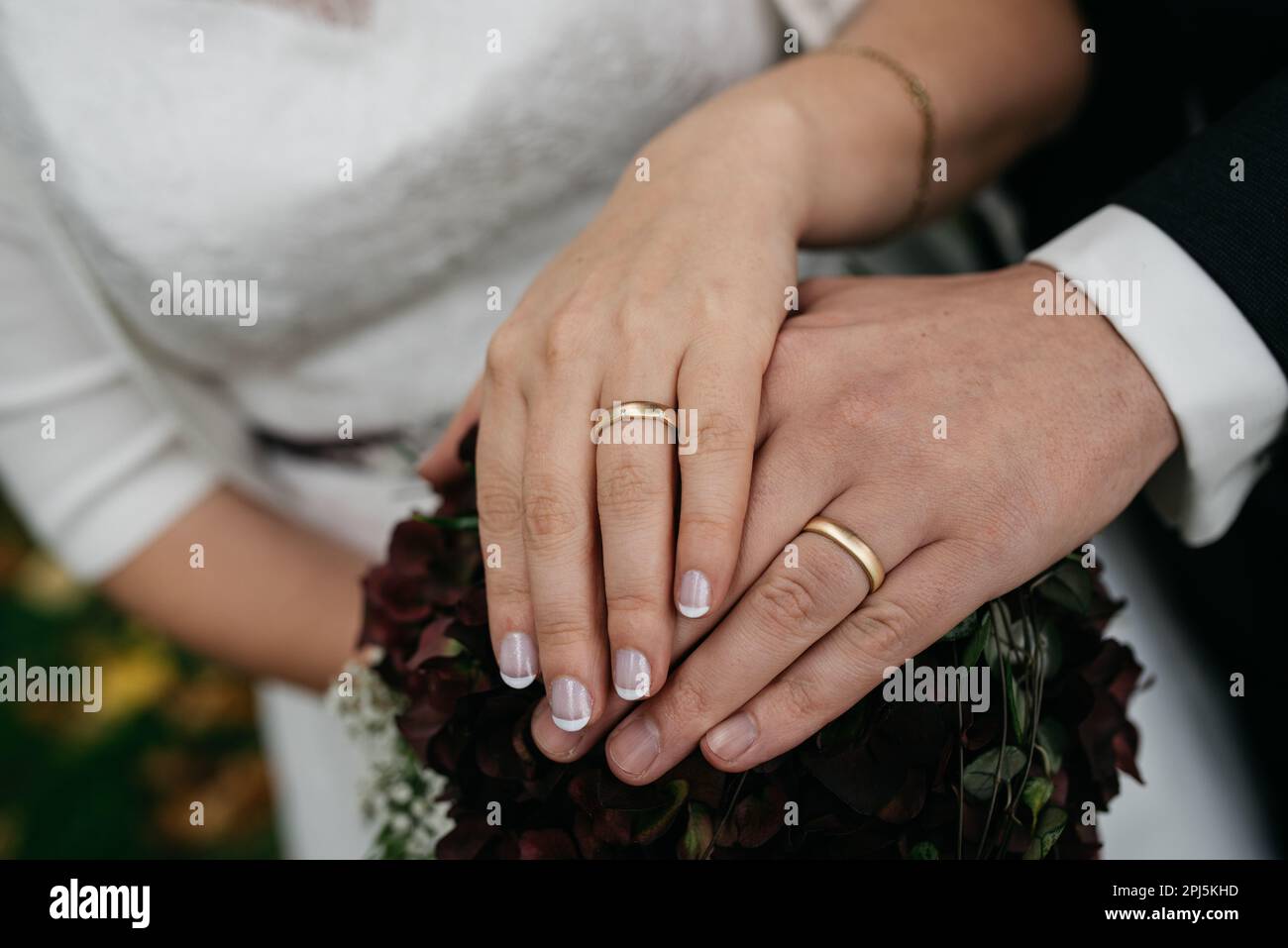 A close-up of a couple's hands featuring their wedding rings ...