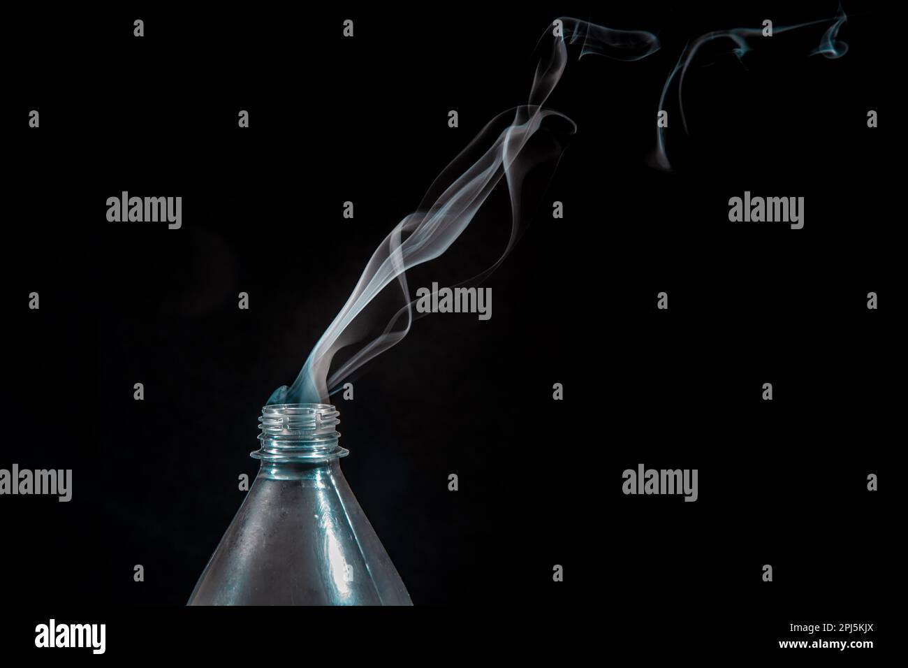 Smoke coming out of a plastic bottle against a black background. Design ...
