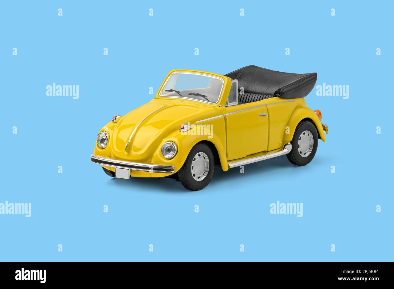 Miniature yellow toy convertible car on blue background with copyspace ...