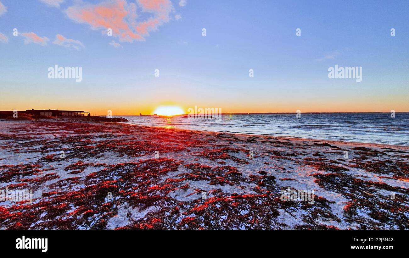 A stunning orange sunset radiates over the ocean, with vibrant red ...