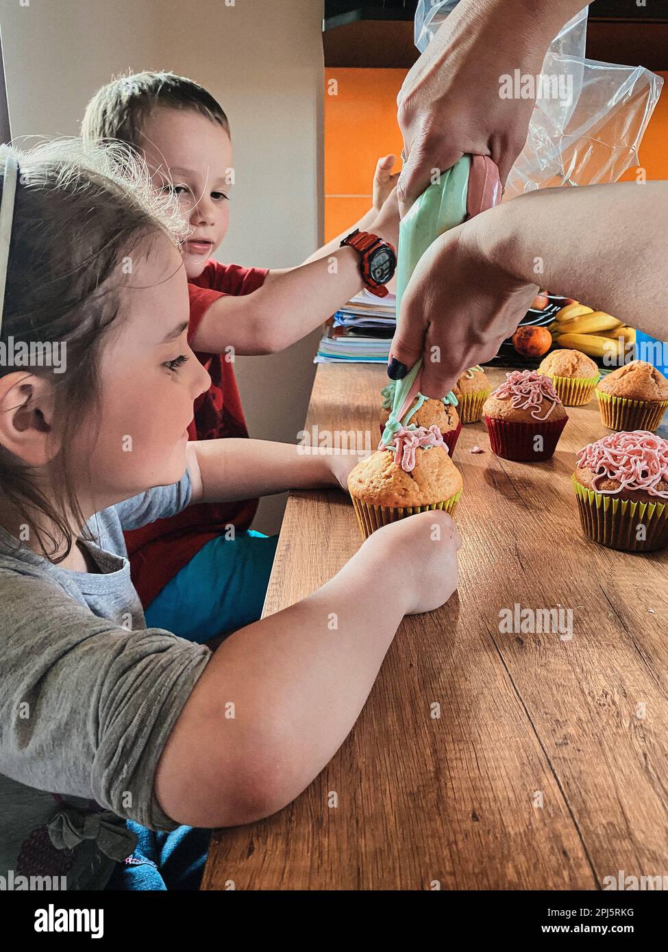 Group of children baking cupcakes, squeezing cream from confectionery ...