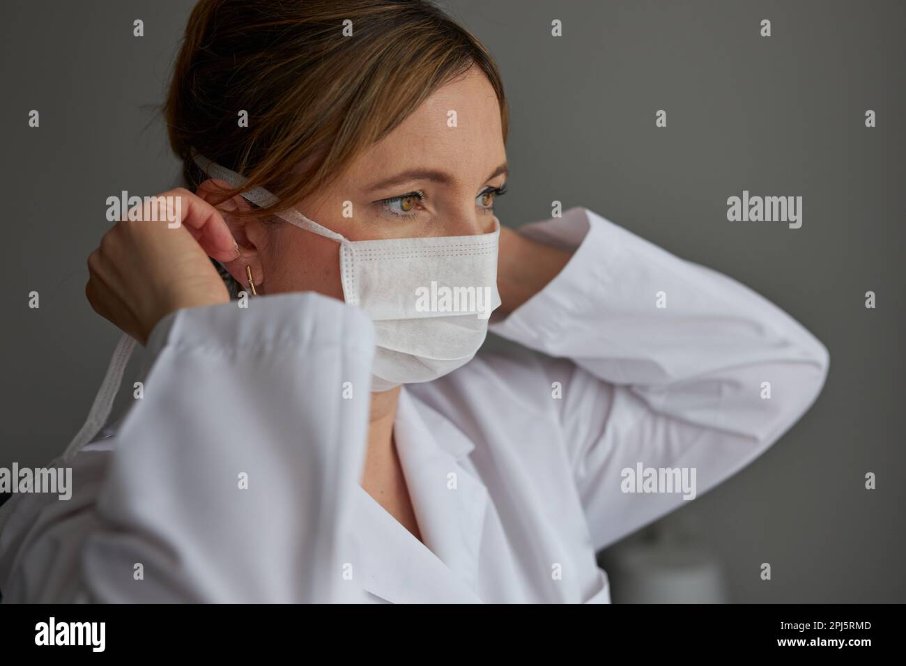 Doctor covering her face with mask. Portrait of young woman wearing the ...
